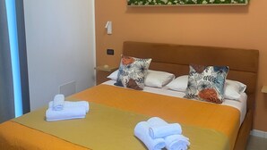 Uma cama bem arrumada com um edredom amarelo, duas almofadas com estampas florais e um relógio de parede.
