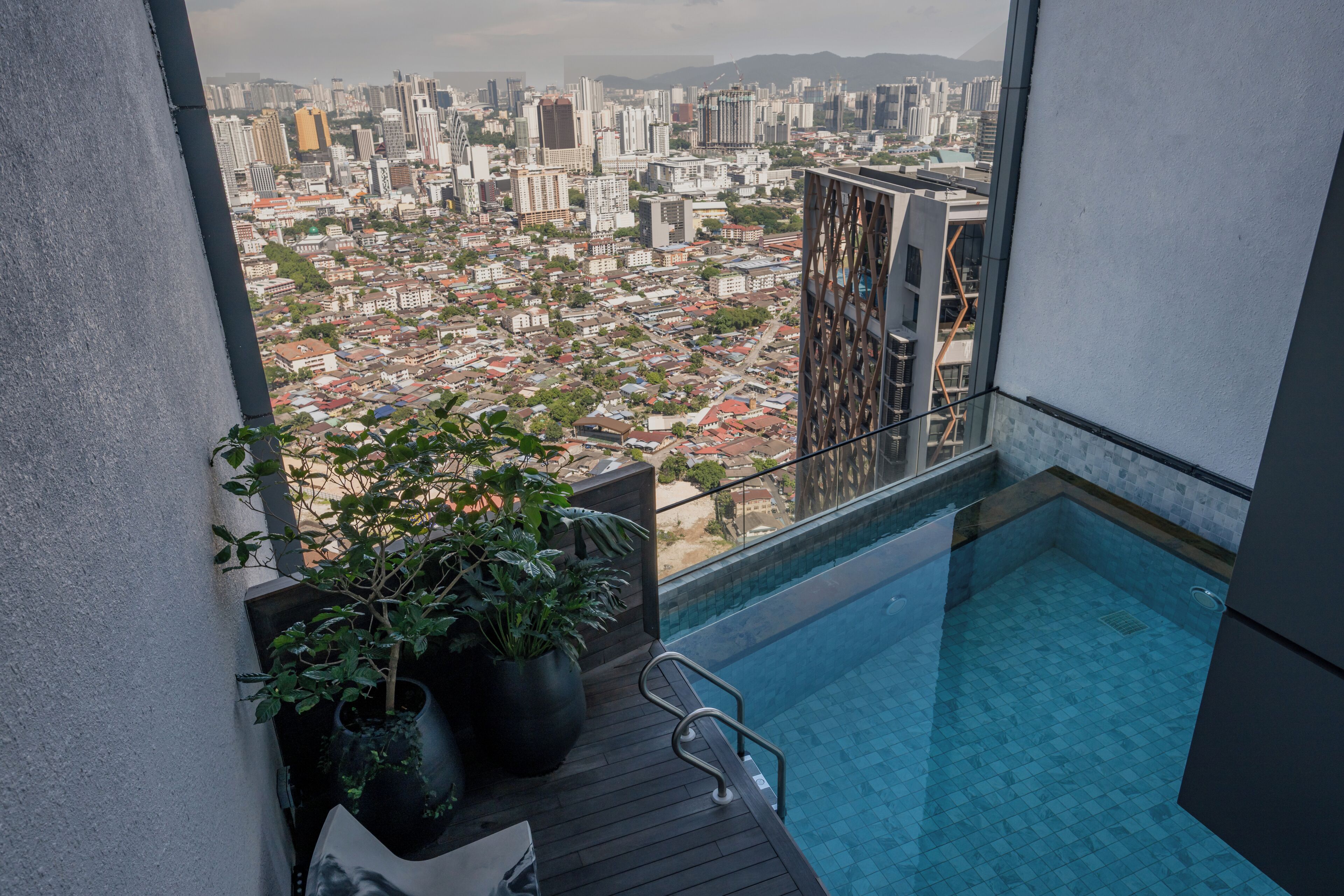 Varanda com piscina, plantas em vasos e vista para a cidade.