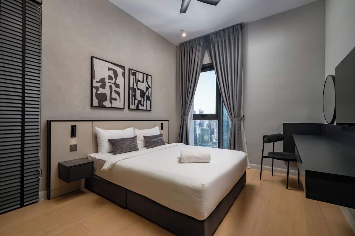 Quarto de hotel moderno com uma cama grande, uma escrivaninha e vista para a cidade.