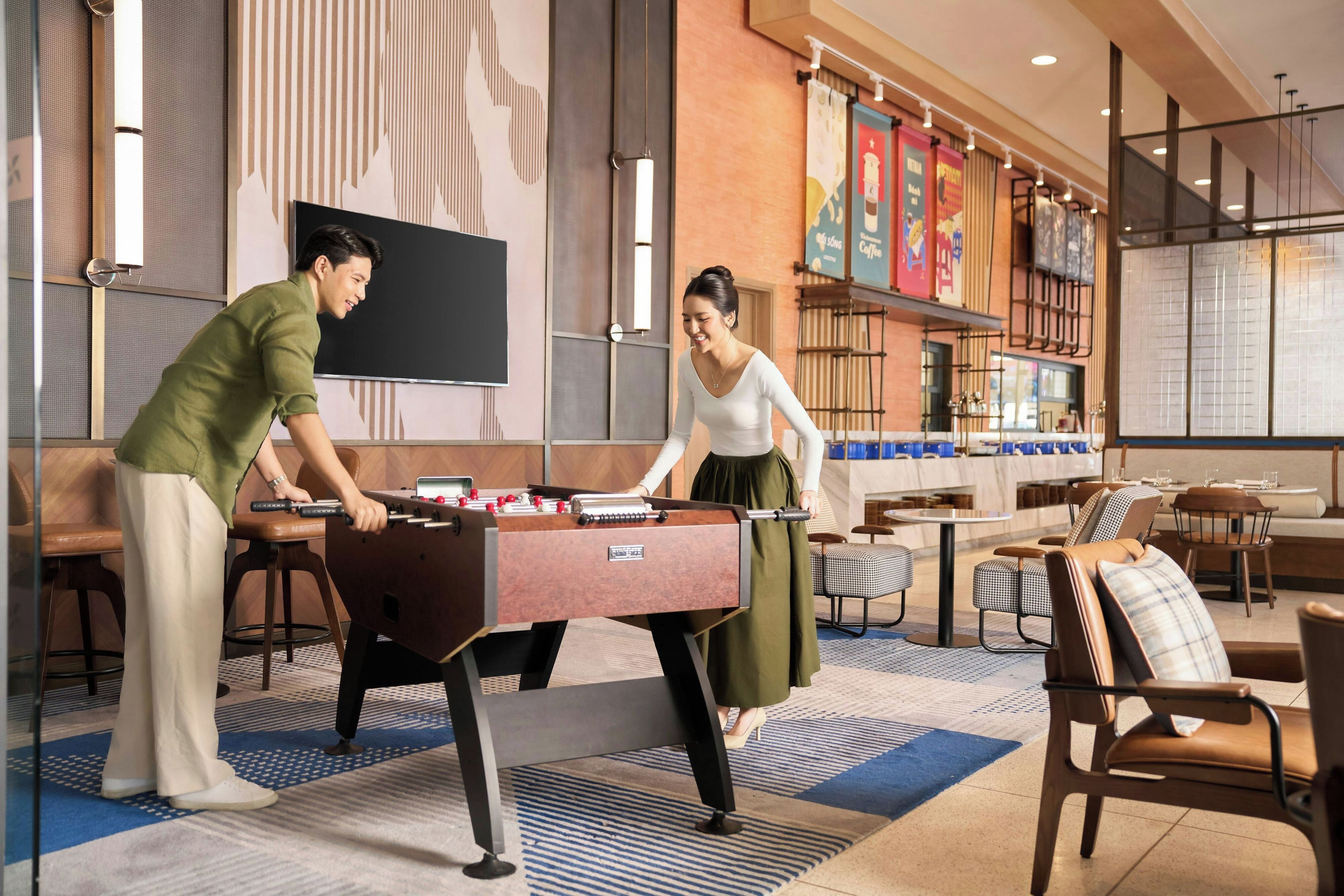 Espaço moderno em ambientes internos com mesa de futebol, áreas de estar e bar com decoração colorida.