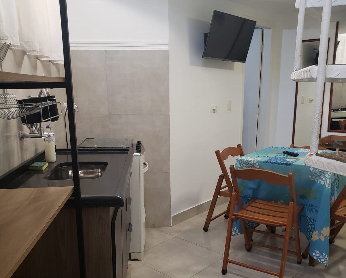 Cozinha compacta com fogão, pia e área de refeições com mesa e cadeiras.