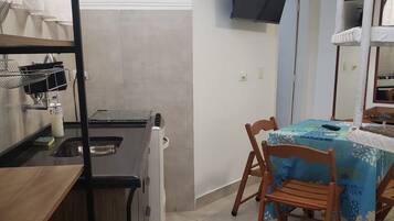 Cozinha compacta com fogão, pia e área de refeições com mesa e cadeiras.