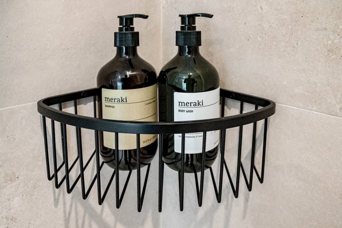 Estante de metal preta com duas embalagens de lavagem corporal e shampoo Meraki.