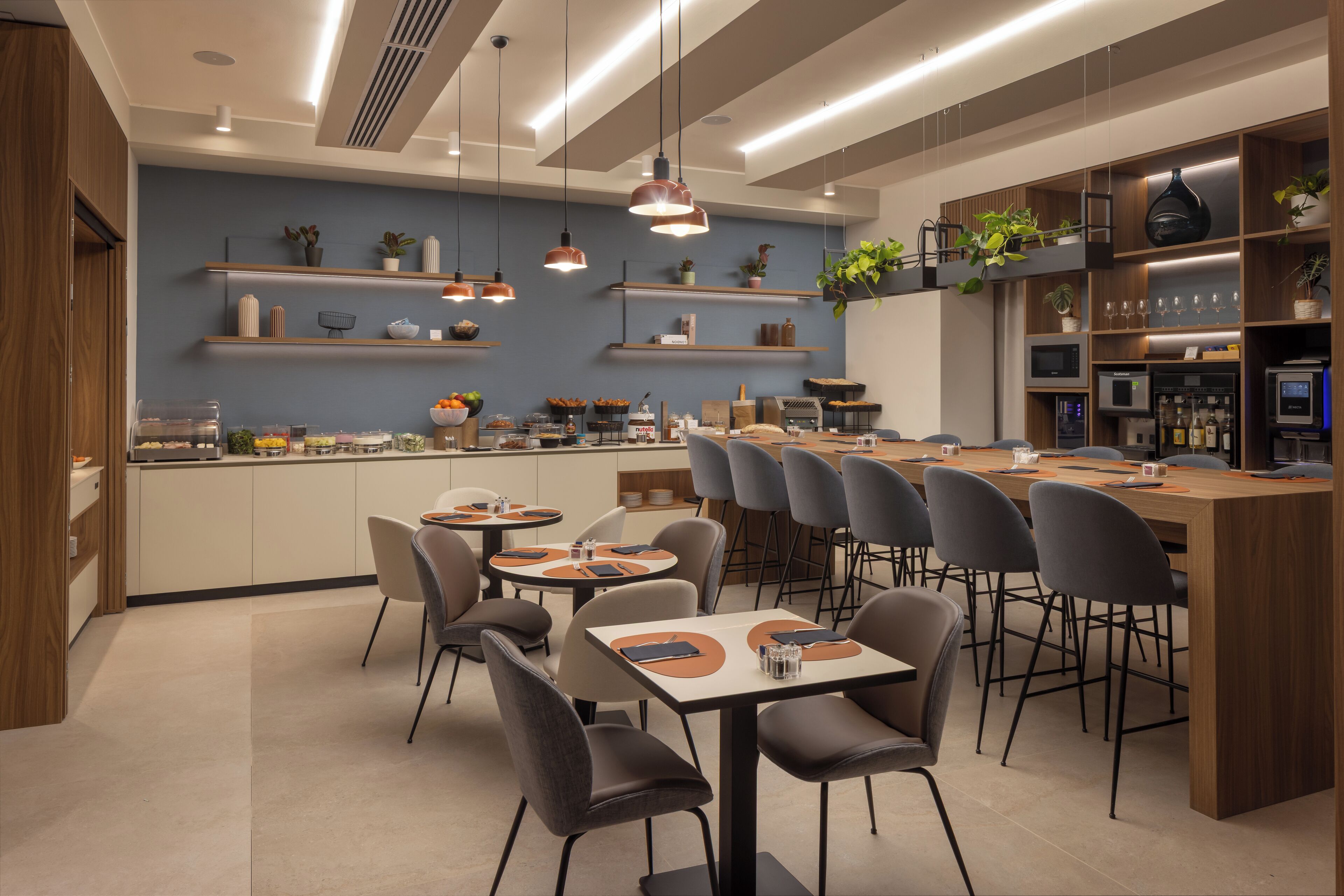 Um restaurante moderno com ilha central, vários espaços de estar e diversos vasos de plantas e eletrodomésticos de cozinha.