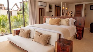 Quarto espaçoso com uma cama grande, um sofá e vista para palmeiras.