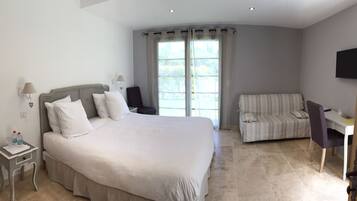 Quarto de hotel com uma cama grande, um sofá, uma mesa de trabalho e uma televisão.