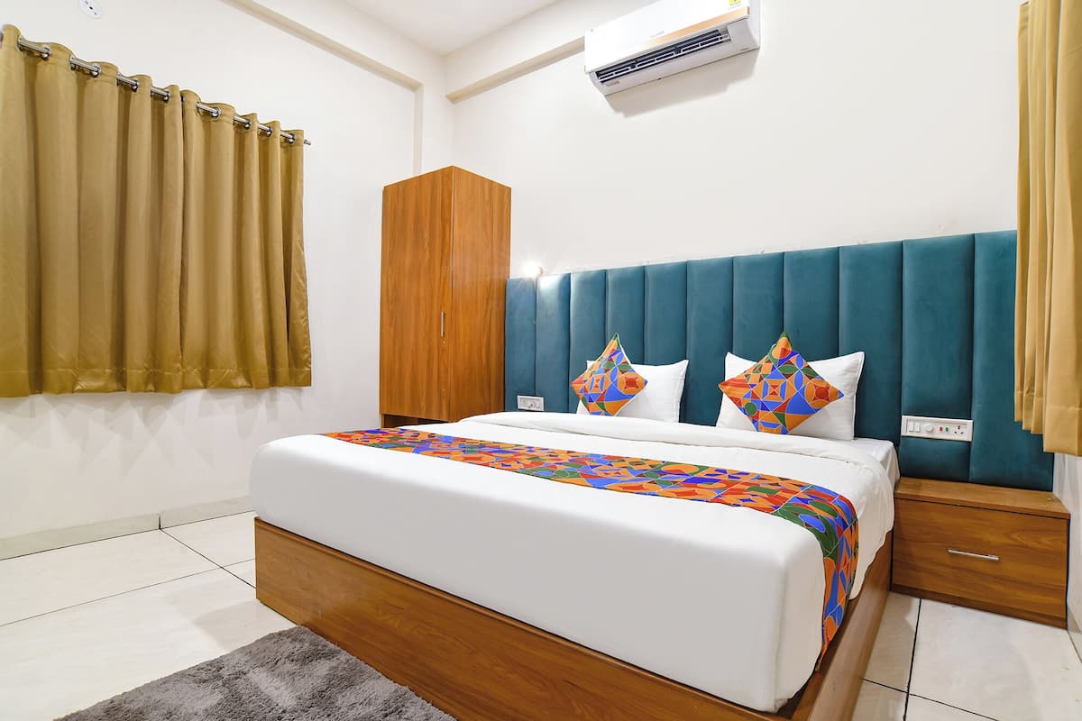 Quarto com cama, guarda-roupa de madeira, cabeceira azul-turquesa e colcha estampada.