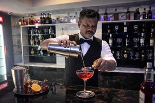 Um bartender servindo uma bebida em uma taça de martini.