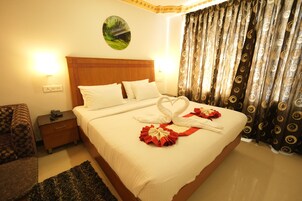Quarto de hotel com uma cama bem arrumada, uma mesa de cabeceira com telefone e um quadro na parede.