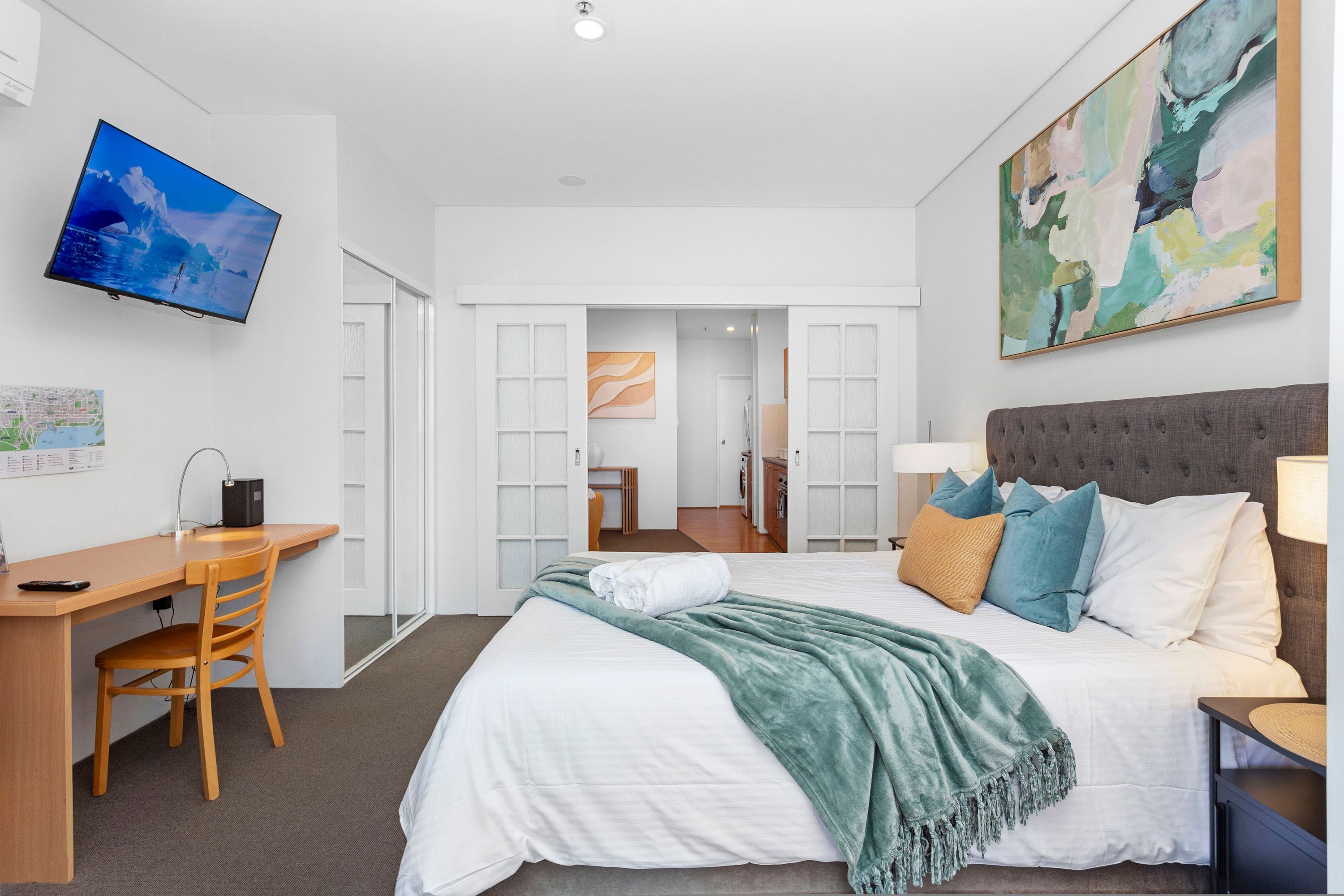 Quarto de hotel moderno com uma cama grande, uma escrivaninha e uma televisão.