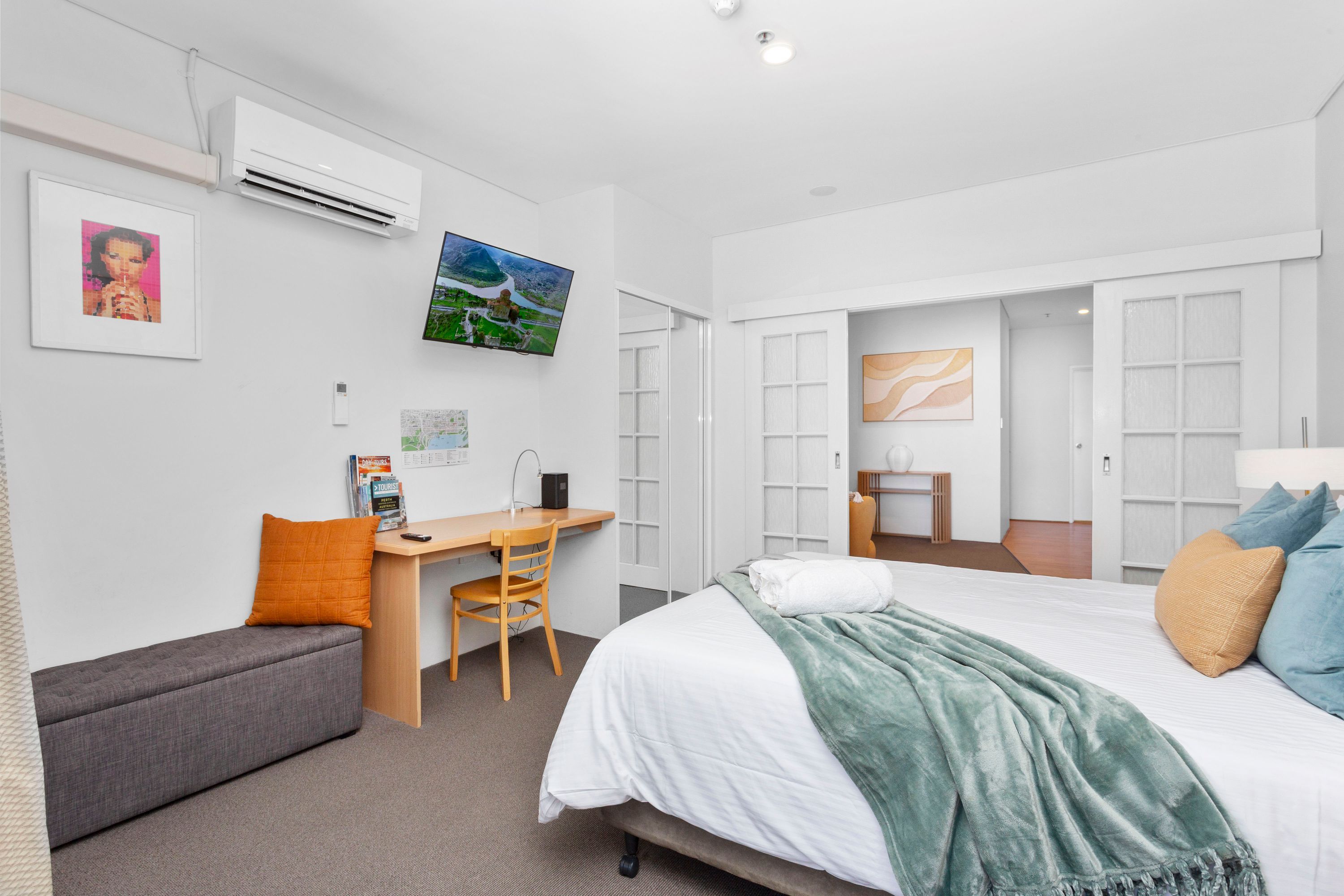 Quarto de hotel moderno com cama, escrivaninha e área de estar.