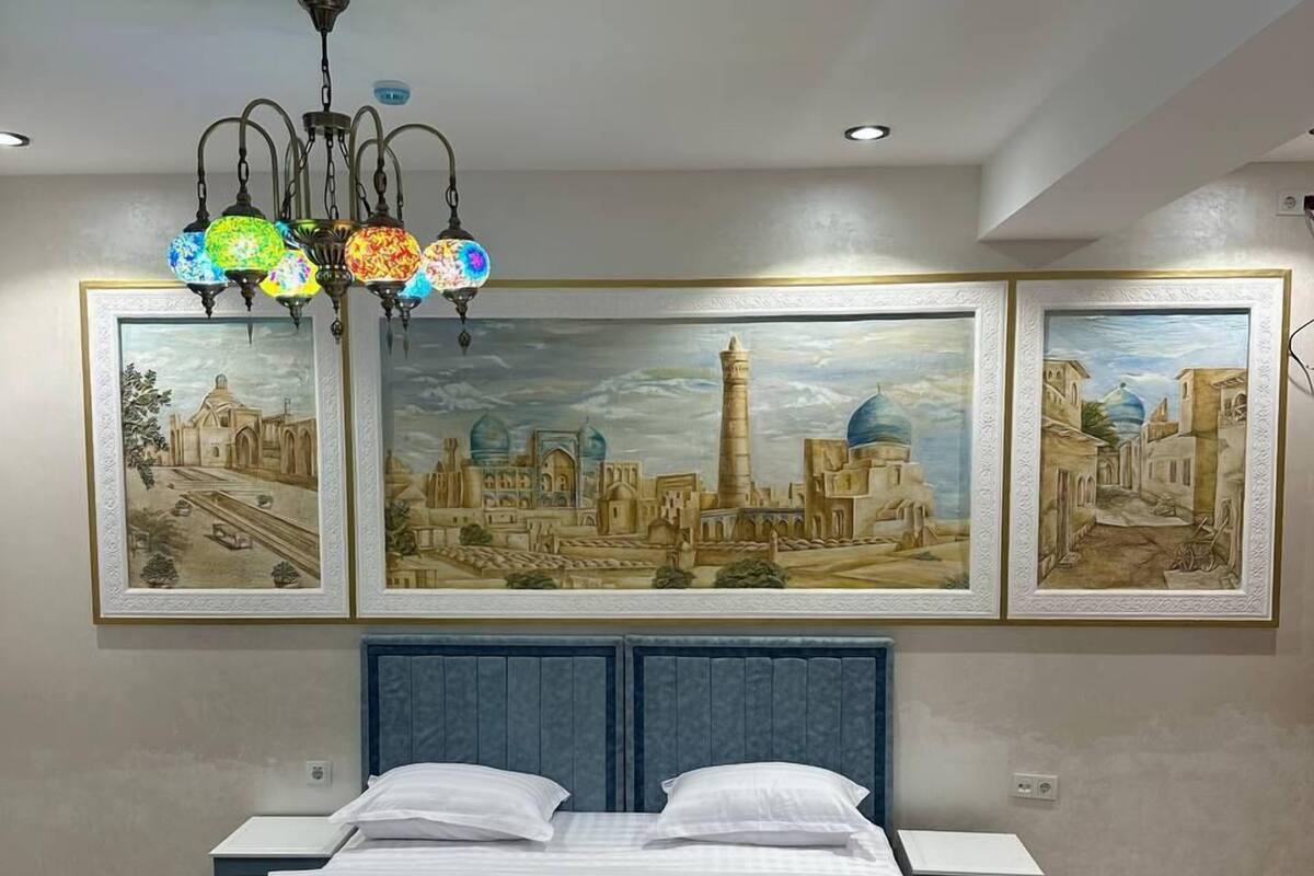 Um quarto com cama, cabeceira e três quadros na parede.