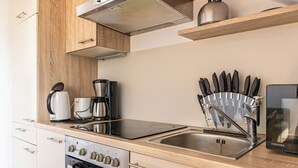 Uma cozinha moderna com forno embutido, fogão, chaleira e porta-facas.