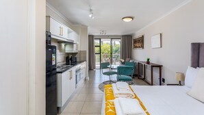 Quarto de hotel com cama, cozinha compacta, área de refeições e varanda com vista.