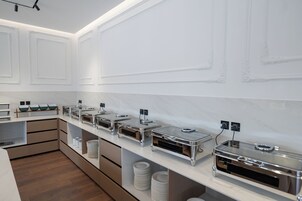 Uma cozinha moderna com paredes brancas, bancadas de mármore e eletrodomésticos de aço inoxidável.