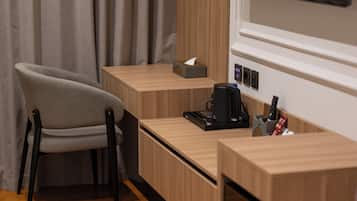 Quarto de hotel moderno com uma mesa de madeira, uma cadeira, uma máquina de café e uma caixa de lenços.