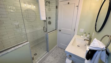 Uma casa de banho com cabine de duche em vidro, uma sanita branca e uma porta.