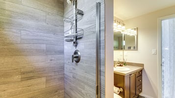 Uma casa de banho moderna com chuveiro, sanita e lavatório.