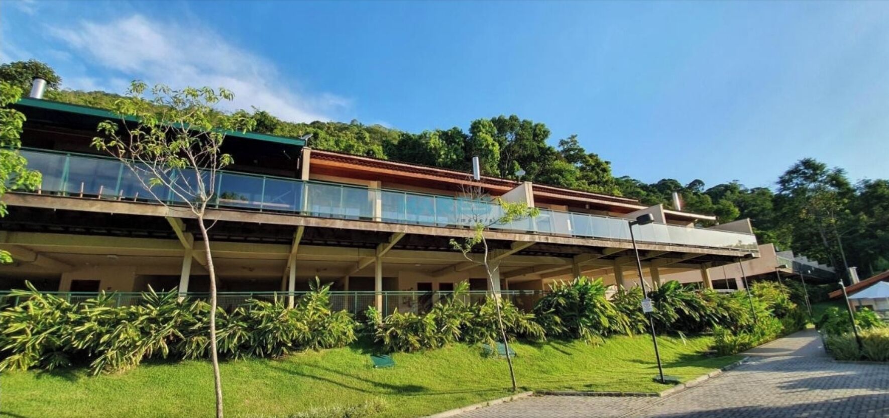 Um edifício moderno com galeria coberta e paisagem verde exuberante.