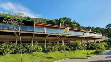 Um edifício moderno com galeria coberta e paisagem verde exuberante.