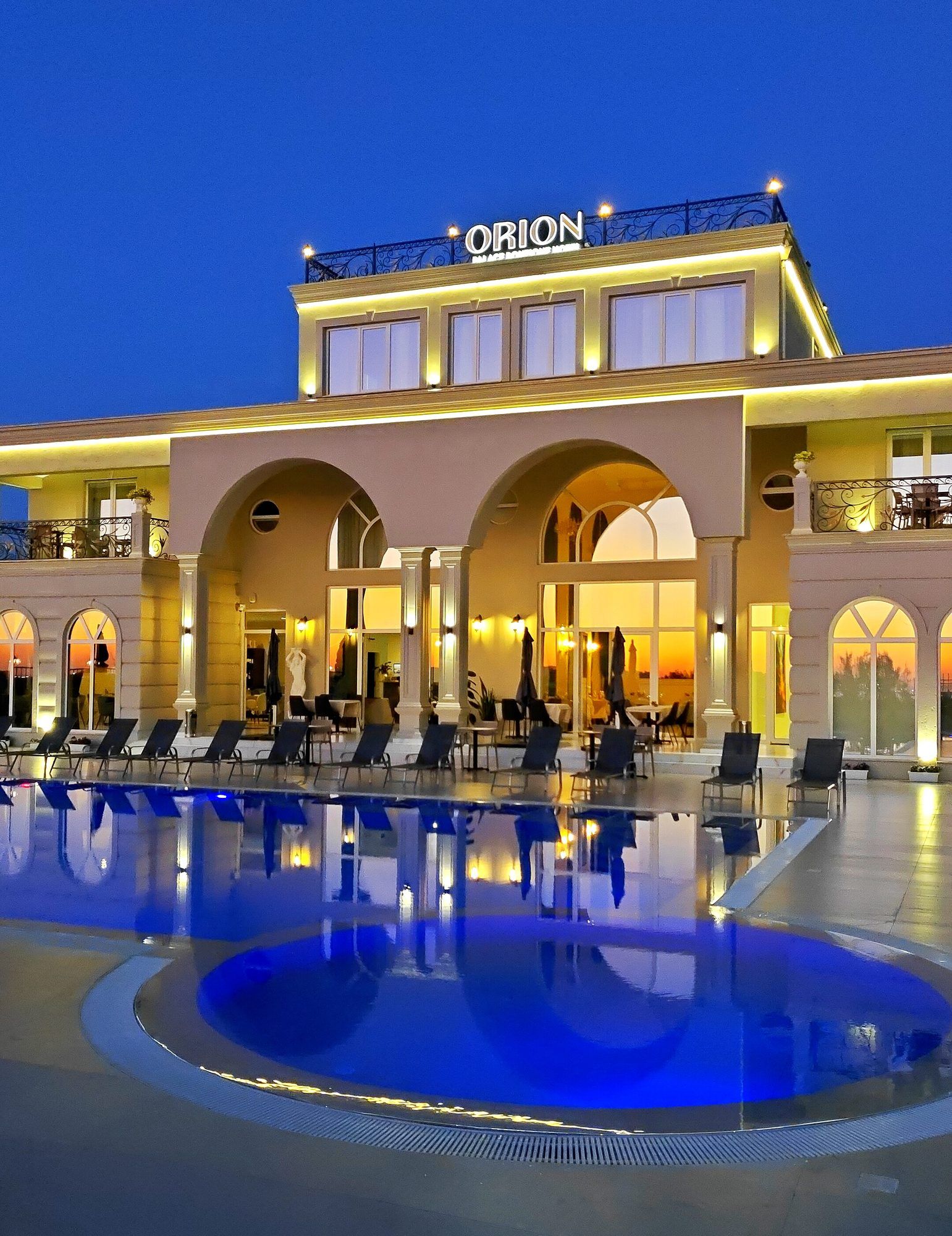 Um hotel com piscina, área de estar externa e uma placa que diz 'ORION'.