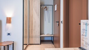 Quarto de hotel moderno com um guarda-roupa de madeira, uma mesinha e um banco.