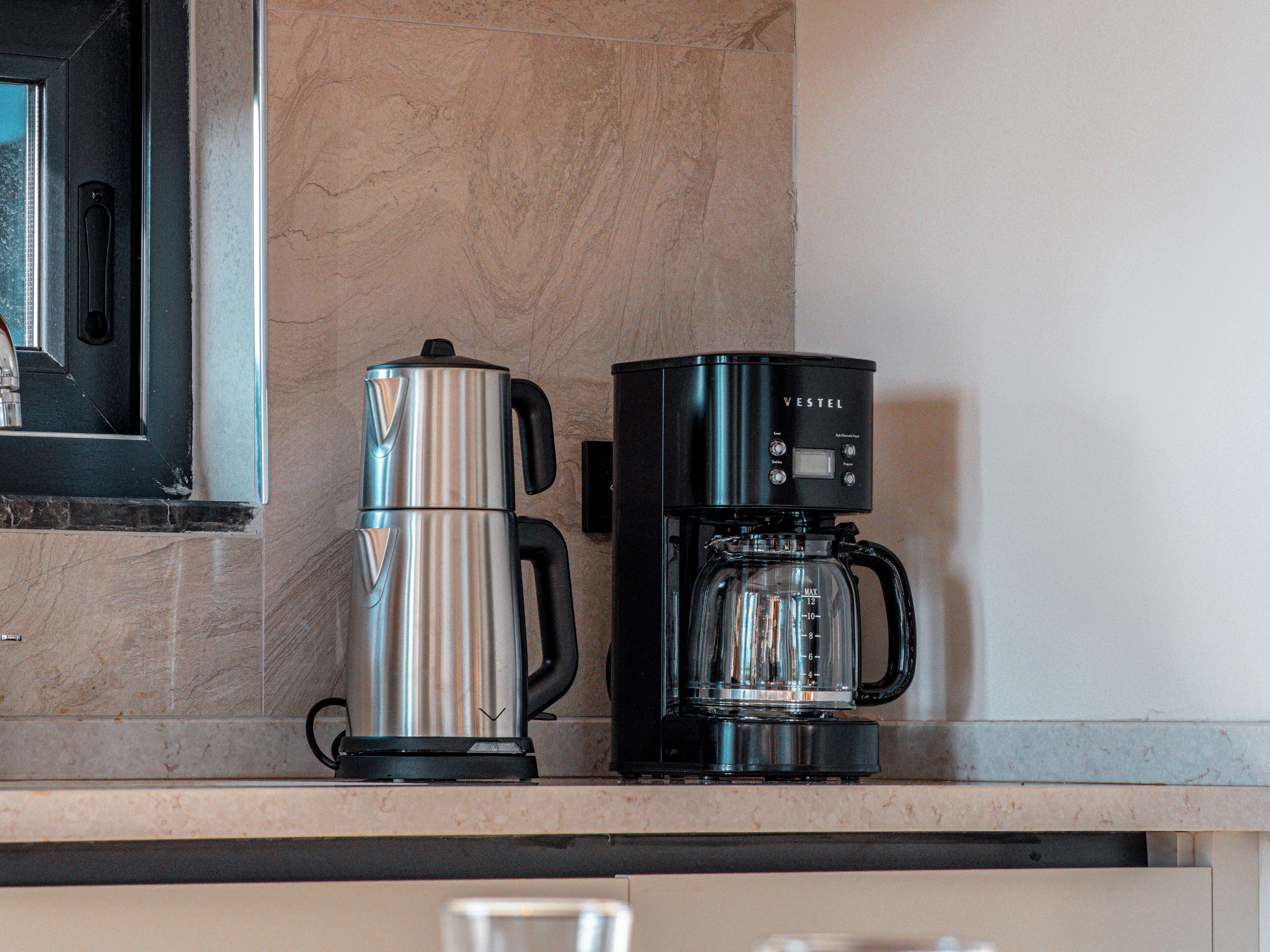 Uma cozinha com uma cafeteira e uma chaleira no balcão.