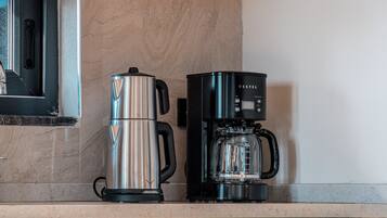 Uma cozinha com uma cafeteira e uma chaleira no balcão.