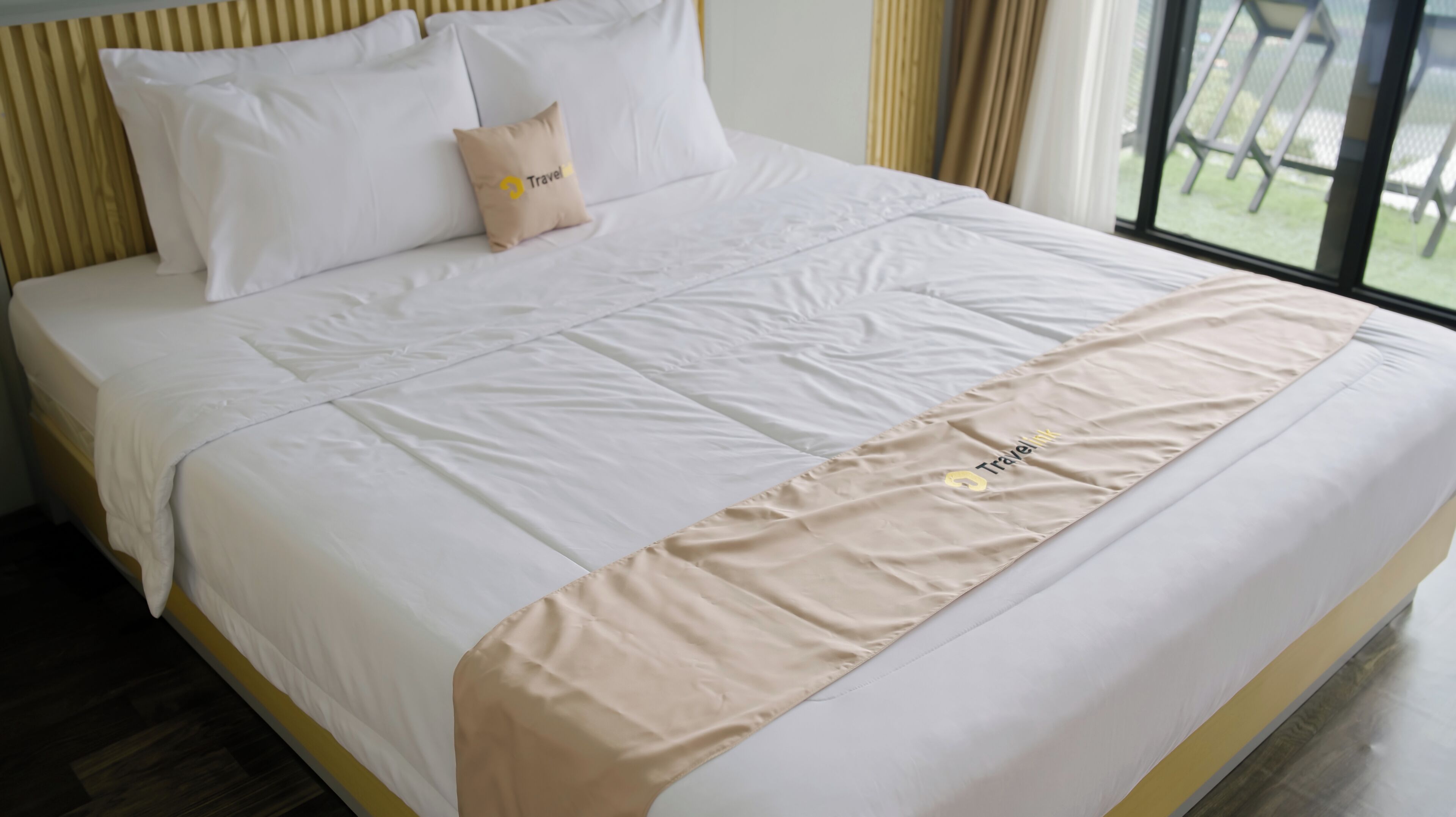 Quarto de hotel com uma cama grande, um travesseiro com logotipo e vista para o exterior pela janela.
