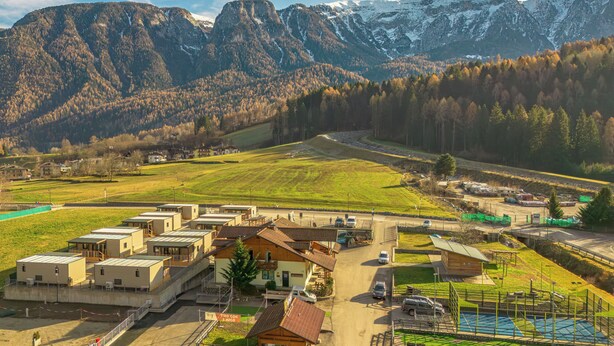 Um resort de montanha com edifícios em estilo chalé, uma piscina e vista para montanhas nevadas.