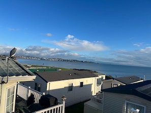Uma área residencial costeira com casas, céu claro e vista para o mar.