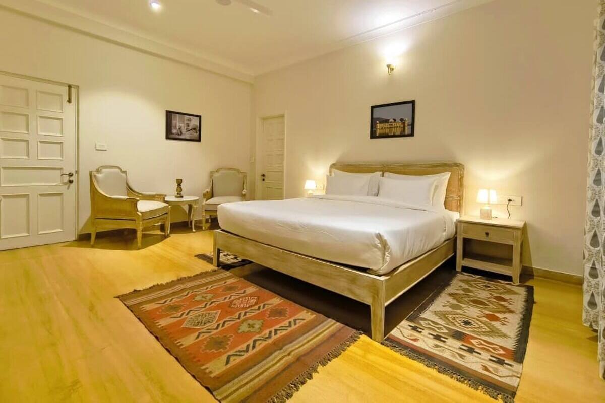 Um quarto com uma cama, uma cadeira, uma mesinha de cabeceira e uma porta.