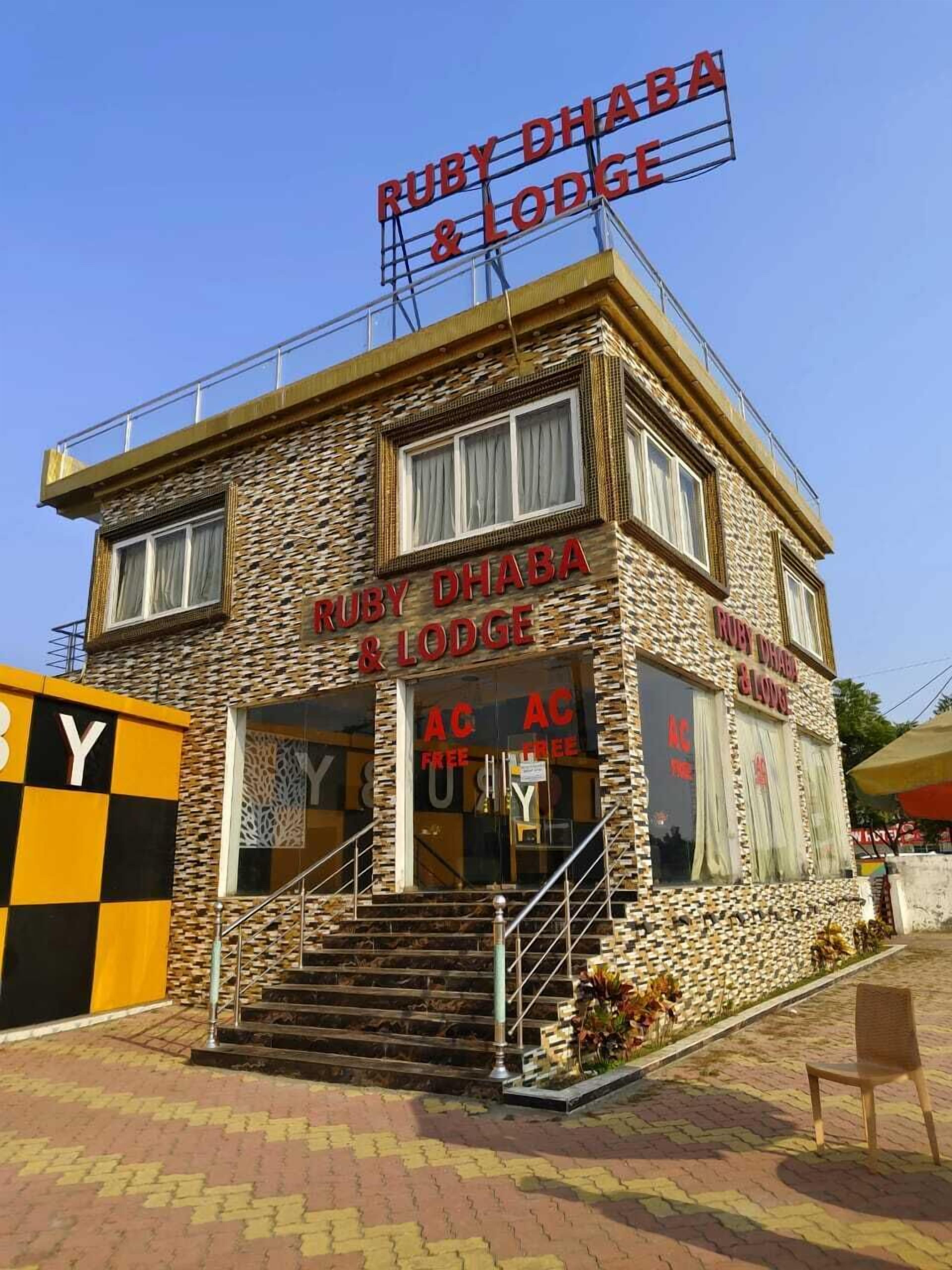 Um edifício de dois andares com fachada de pedra e uma placa com a inscrição "Ruby Dhaba & Lodge".