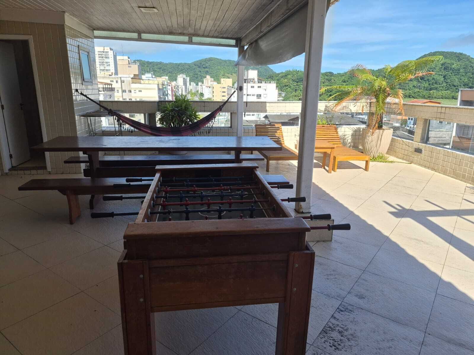 Uma área externa com mesa de pebolim, bancos e rede.