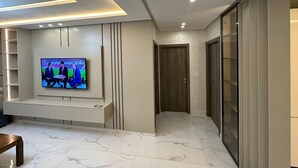 Uma sala de estar moderna com televisão de tela plana na parede, piso de mármore e prateleiras embutidas.