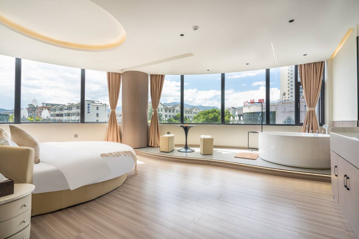 Quarto moderno com cama grande, banheira e vista para a cidade.