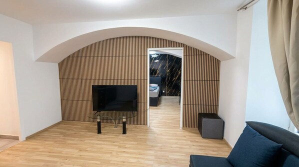 Uma sala de estar moderna com uma TV de tela plana, um sofá, uma mesinha e um painel de parede de madeira.
