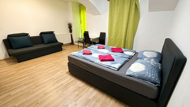 Quarto moderno com cama, sofá, mesa de jantar e cadeiras.