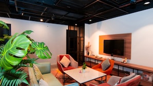 Um interior moderno com um sofá, cadeiras, uma mesa e uma televisão na parede.