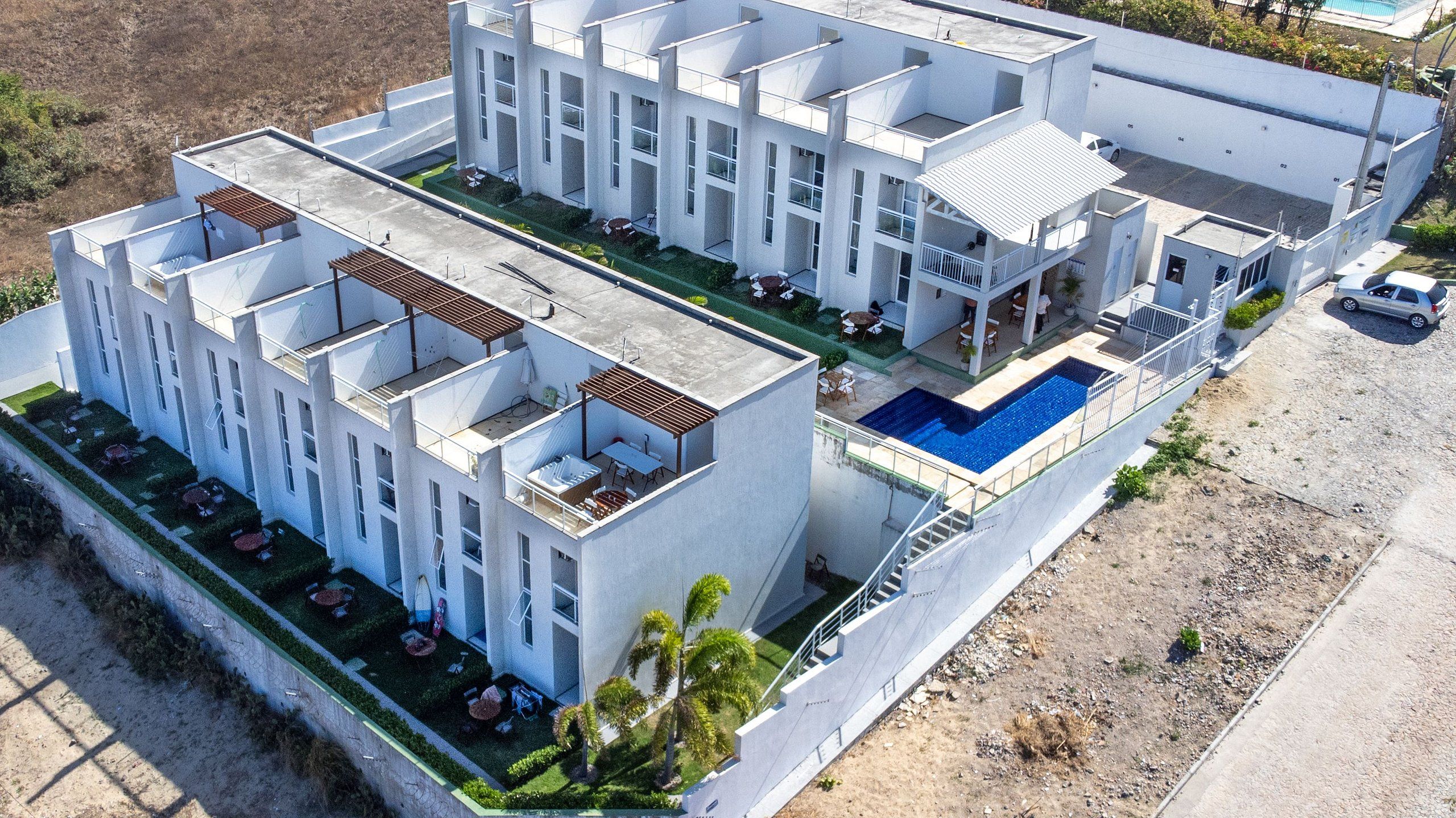 Um hotel moderno com várias varandas, piscina e áreas de estar ao ar livre.