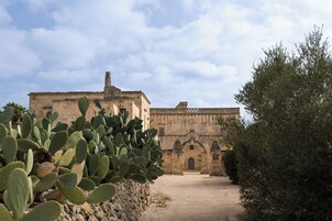 Um edifício histórico com uma entrada em arco e um caminho de pedras que o leva até ele.