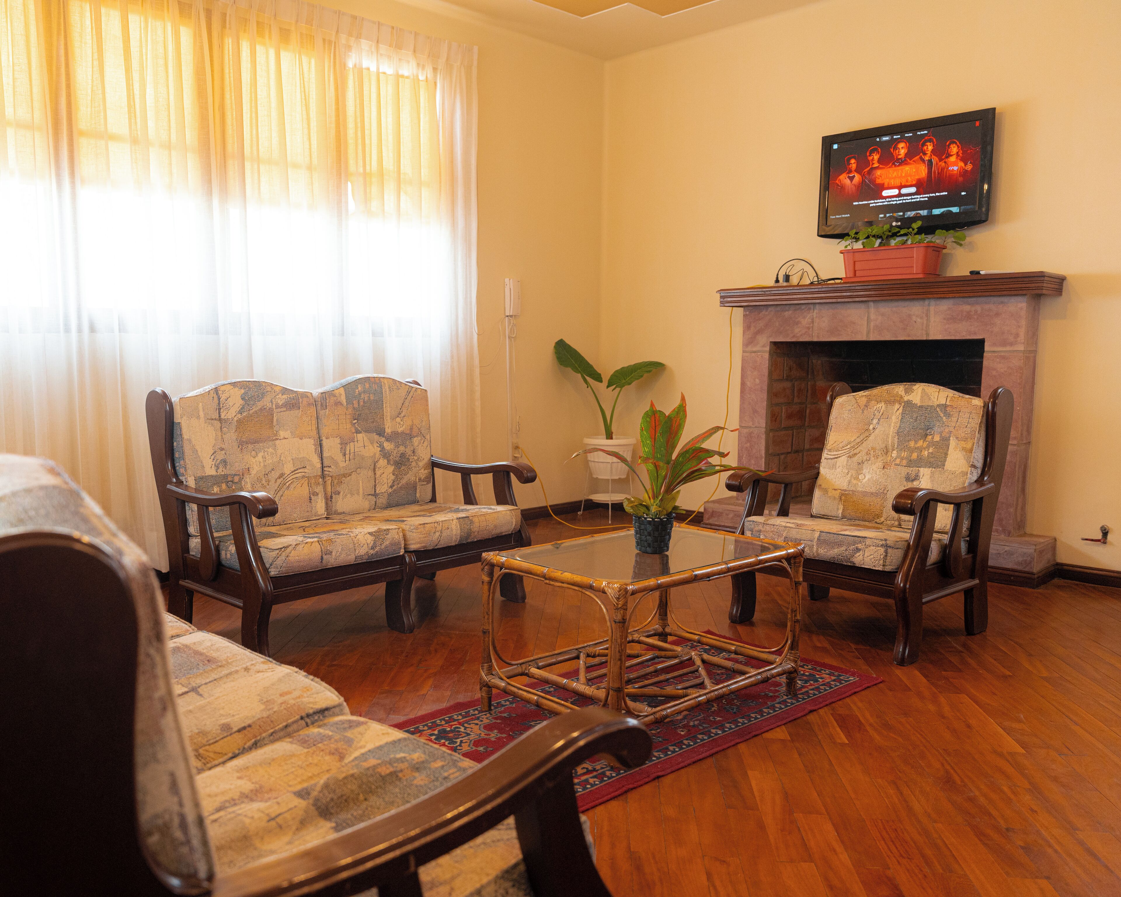 Uma sala de estar com duas poltronas, uma mesa de centro e uma lareira.