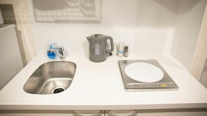 Uma bancada de cozinha com pia, chaleira e balança digital.