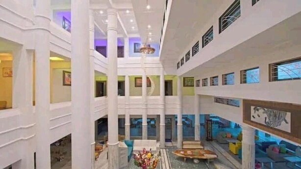 Um amplo hall com pé direito alto, piso de mármore e área de estar central com sofás e uma mesa de centro.