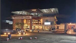 Hotel com fachada de vidro, vários andares e área de estacionamento.