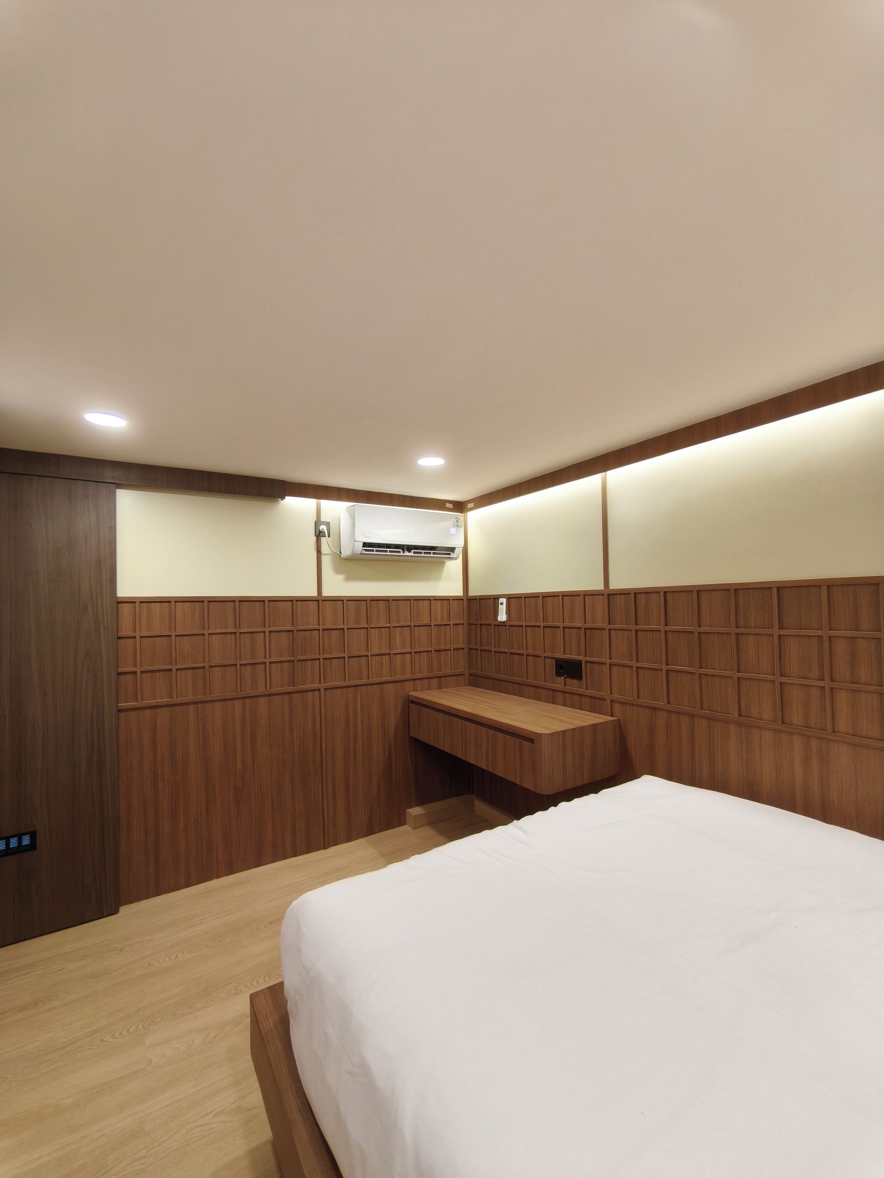 Quarto de hotel com uma cama, uma penteadeira de madeira, um espelho e um ar condicionado.