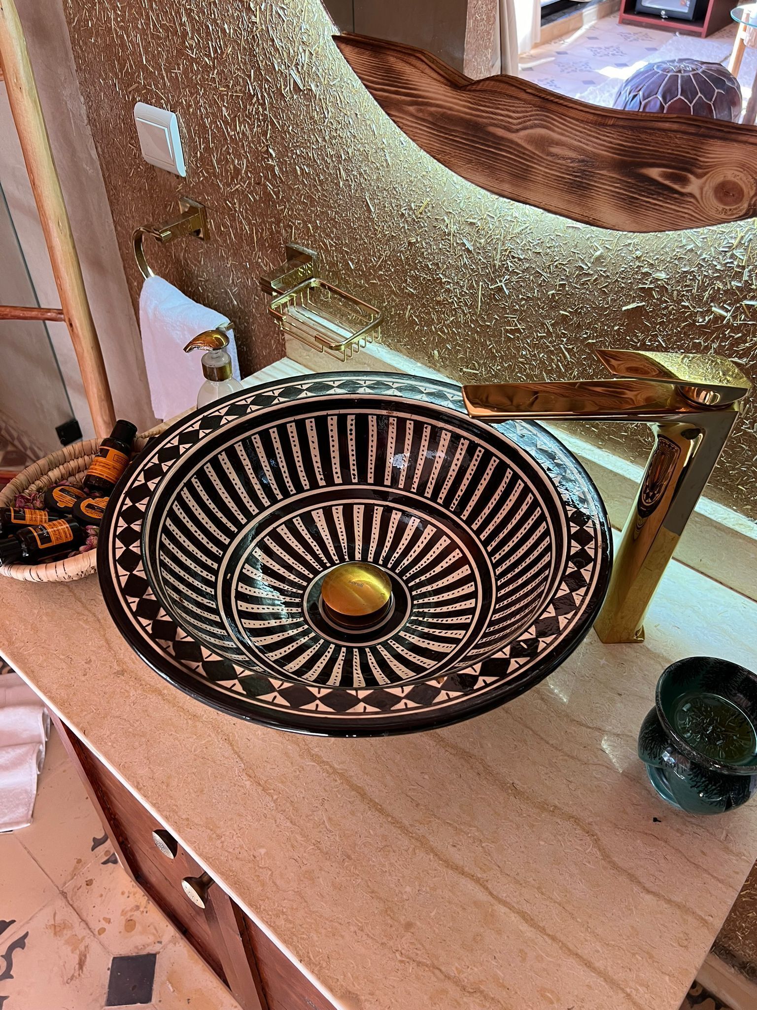 Uma bancada de cozinha com um prato decorativo, uma garrafa de azeite e uma tigela verde.