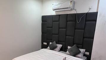 Quarto moderno com uma cama grande, cabeceira, aparelho de ar condicionado e piso de mármore.
