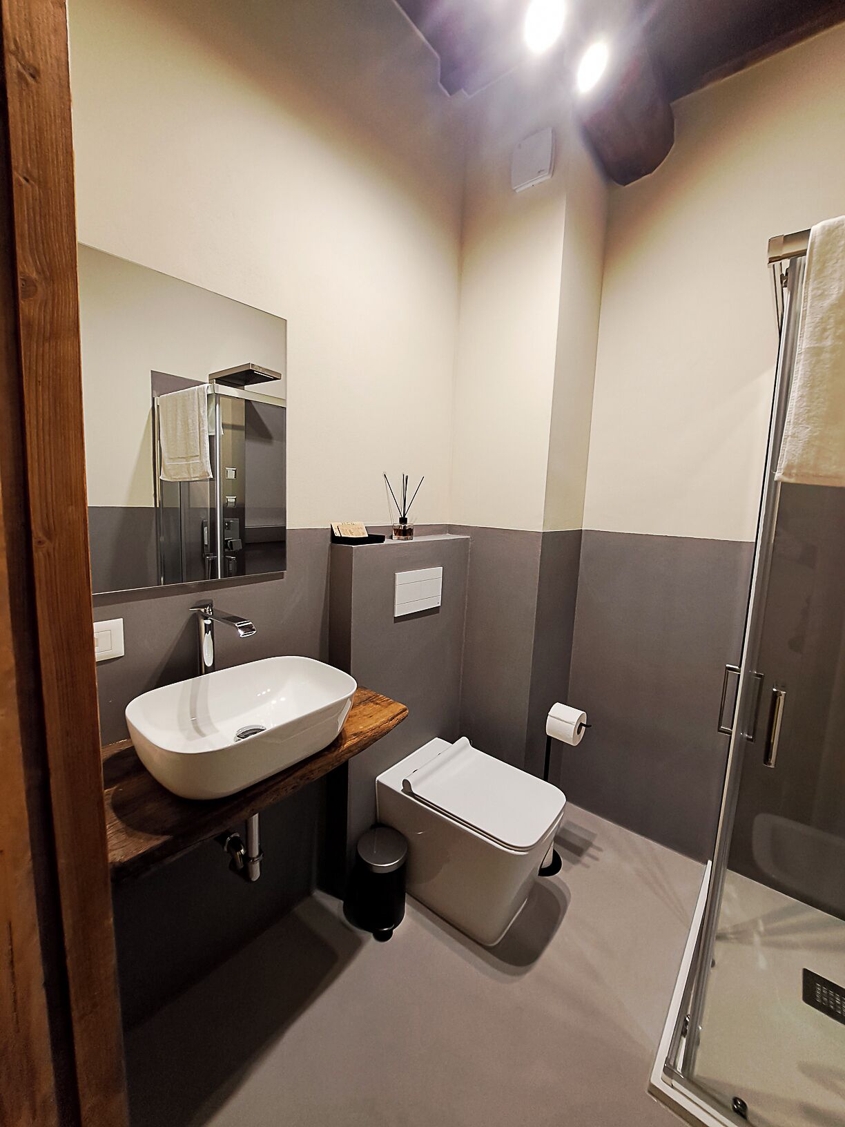 Uma casa de banho moderna com uma grande pia branca, um espelho, uma sanita e uma zona de duche.