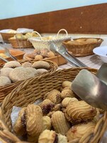 Uma mesa de buffet com diversos alimentos, incluindo bolachas e doces, dispostos em cestas.
